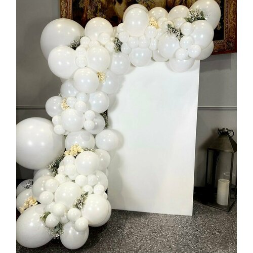 Белая фотозона из латексных шаров с декоративными цветами и баннером